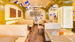 Um restaurante com cabines e mesas, decorado com balões e um mural de árvore na parede.