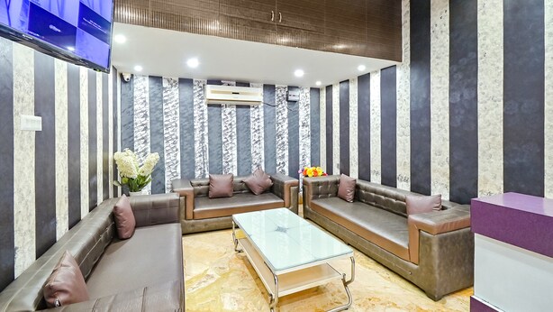 Uma sala de estar moderna com paredes listradas, sofás de couro, uma mesa de centro de vidro e uma televisão de tela plana na parede.
