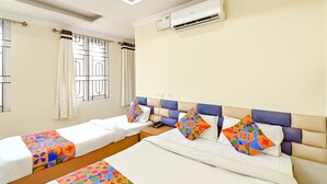 Quarto de hotel com duas camas de solteiro, uma janela grande com cortinas, um ar condicionado e um telefone na mesa de cabeceira.