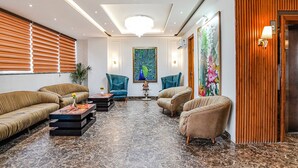 Um hall moderno com piso de mármore, sofás de couro e um candelabro.