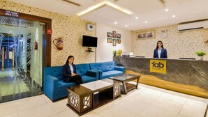 Uma área de recepção de hotel com um sofá azul, um balcão de recepção e um sinal com 'fab hotels'.