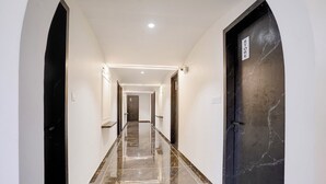 Um corredor com piso de mármore, paredes brancas e uma porta escura com a placa 'STORE'.