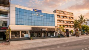 Um hotel moderno com um destaque para a placa 'Hotel Global Inn', fachada em vidro ampla e entrada visível com degraus que levam ao saguão.