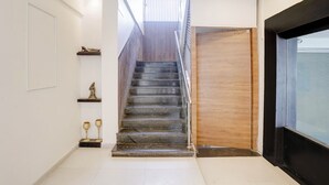 Uma escada com corrimão de metal, uma porta de madeira e uma janela com persianas.