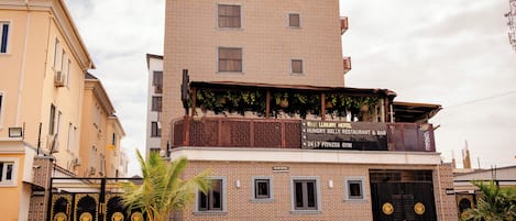 Edifício com vários andares e uma placa indicando ser um hotel de luxo aberto 24 horas por dia.