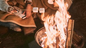 Alguém assando marshmallows em uma fogueira.
