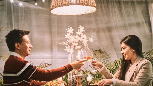 Uma mesa de jantar com velas, um vaso de flores e um abajur de vime.