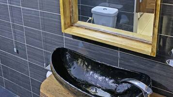 Casa de banho com lavatório preto, toucador de madeira e espelho com moldura de madeira.