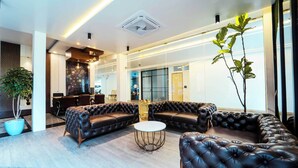 Uma área de estar moderna com sofás de couro, uma mesa de centro redonda e uma planta em vaso.