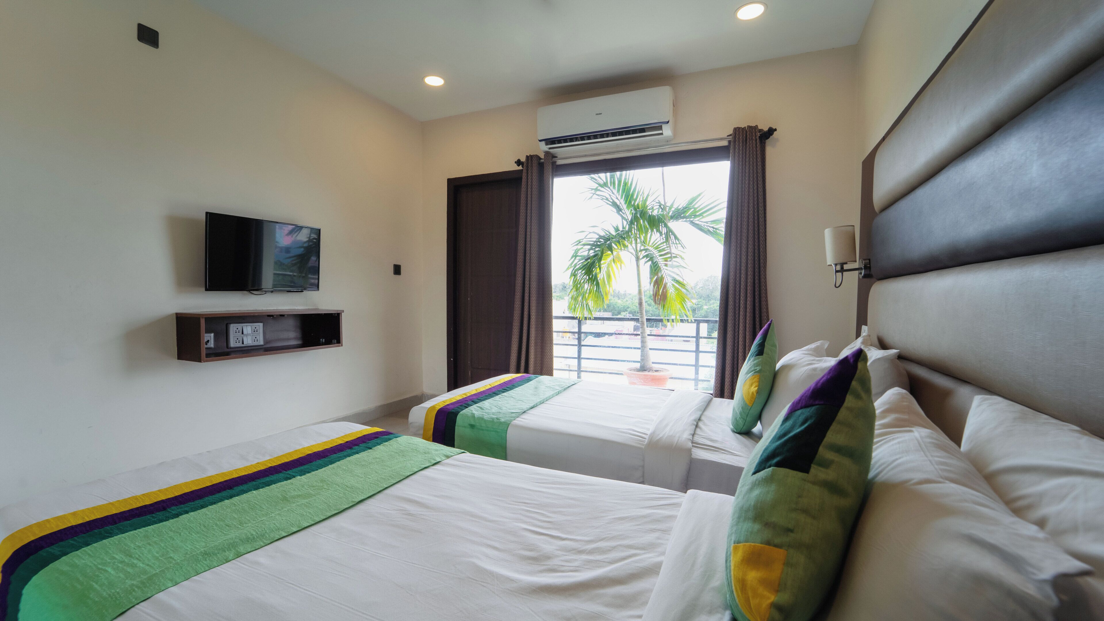 Quarto de hotel com duas camas, televisão, ar condicionado e janela com cortinas.