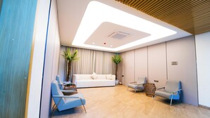 Uma sala de estar moderna com um sofá branco, duas poltronas, uma mesa de centro e teto de madeira.
