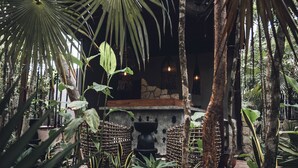 Um jardim interno com parede de pedra, um vaso preto e cestos trançados.