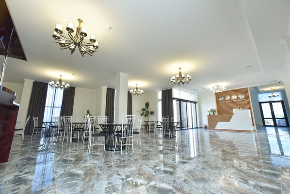 Um hall amplo com piso de mármore, vários espaços de estar e lustres decorativos.