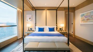 Quarto de hotel moderno com uma cama grande, mesas de cabeceira e vista para a cidade.