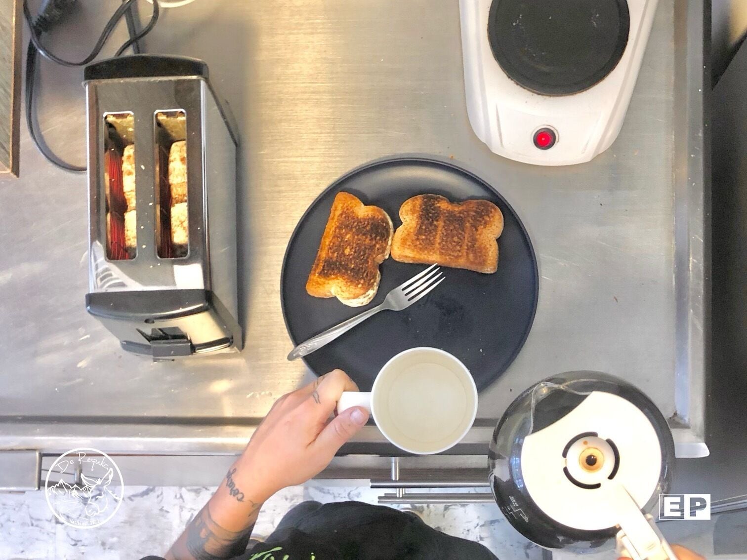 Uma bancada de cozinha com uma torradeira, duas fatias de pão torrado em um prato, um garfo, uma caneca e uma cafeteira.