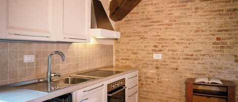 Uma cozinha com armários brancos, pia de aço inoxidável, lava-louças e forno.