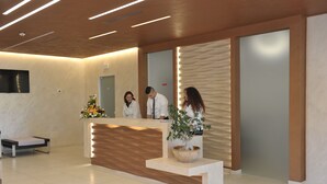 Uma área de recepção com design moderno, com um balcão, um vaso de planta e um espaço de estar.