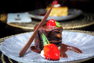Sobremesa em um prato com cobertura de chocolate, uma morango e uma folha de hortelã.