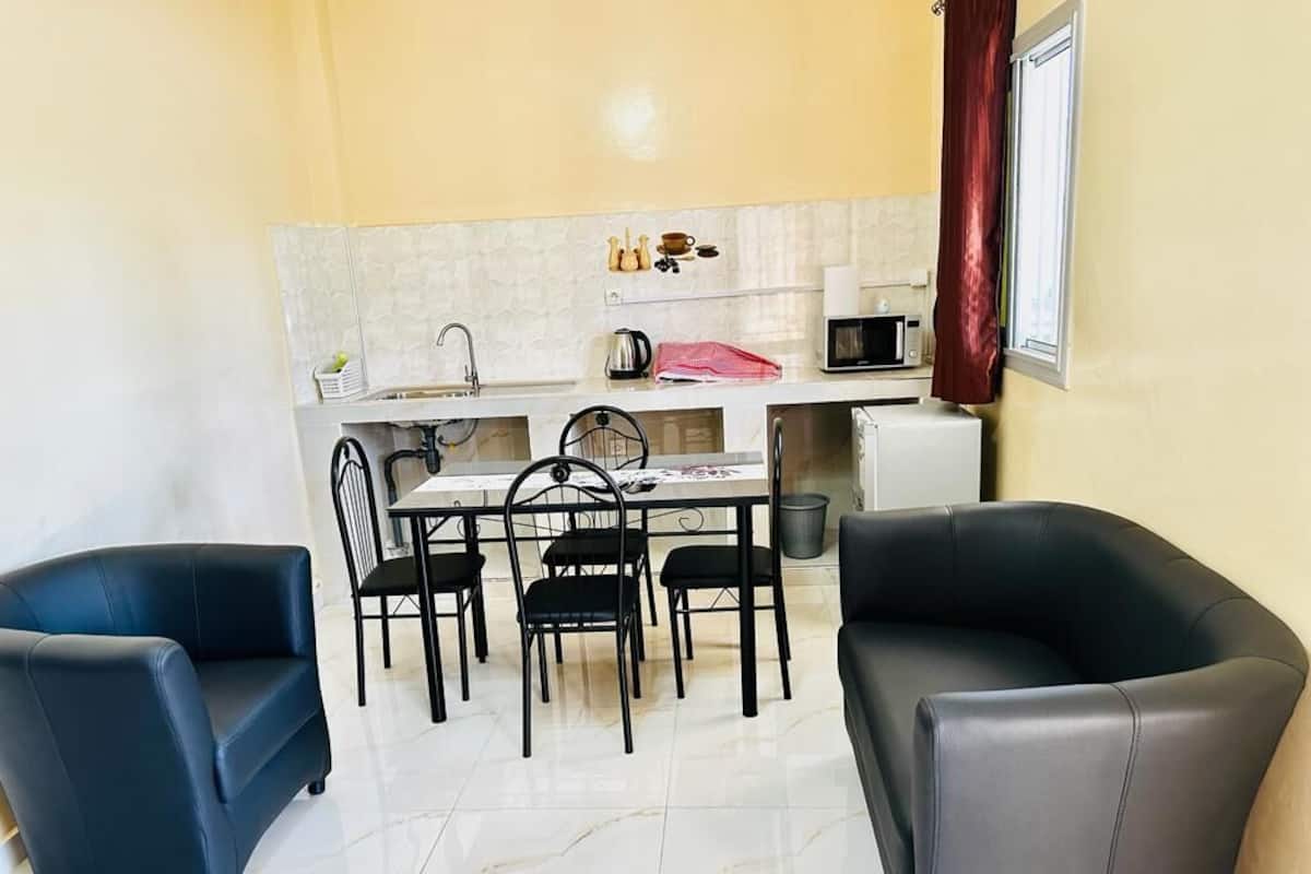 Uma cozinha compacta com uma mesa de jantar e cadeiras, um micro-ondas e uma pia.