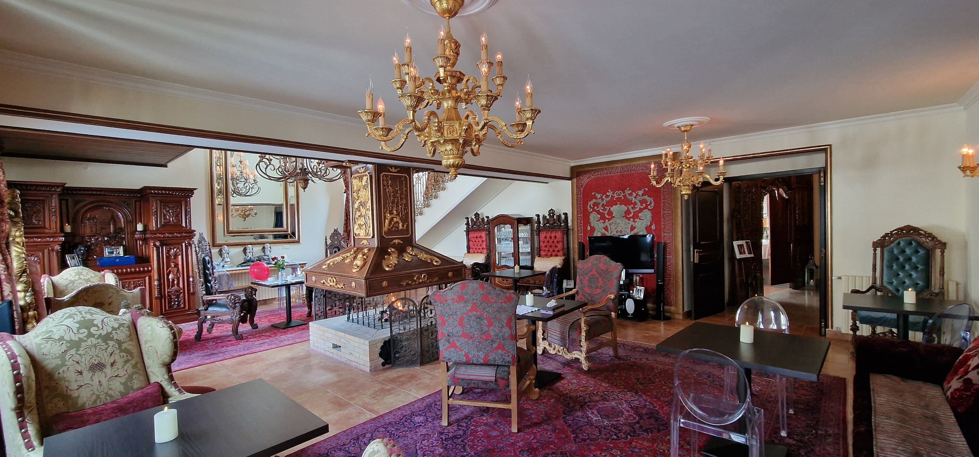 Uma sala imponente com móveis ricamente decorados, um candelabro e um espelho grande.