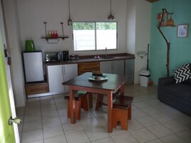 Uma cozinha compacta com uma mesa de jantar e bancos, geladeira, micro-ondas e pia.
