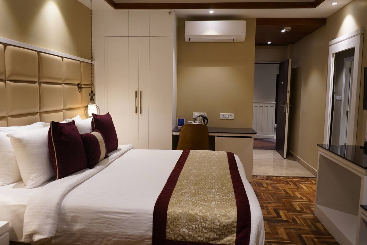Quarto de hotel com uma cama grande, uma escrivaninha e um aparelho de ar condicionado.