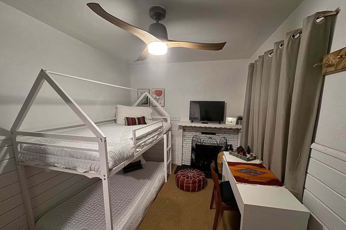Um quarto com uma cama beliche, uma escrivaninha, uma televisão e uma lareira.