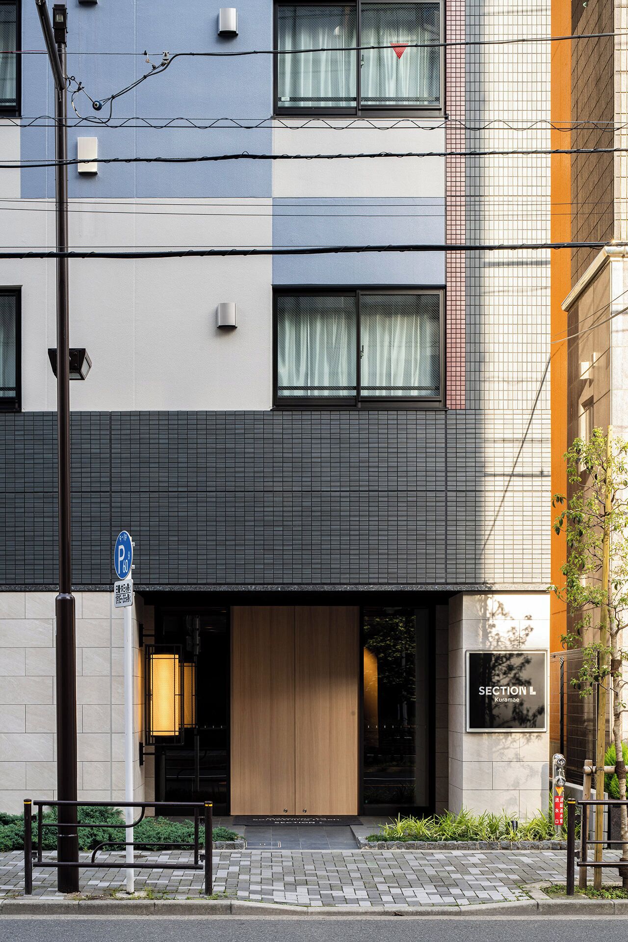 Um edifício moderno com uma entrada ampla, uma placa de estacionamento azul e uma placa indicando 'Seção L'.