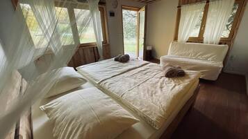 Quarto com duas camas, piso de madeira e janelas amplas com cortinas.