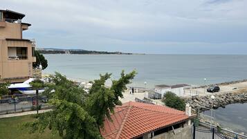 Um hotel à beira-mar com telhado de telhas vermelhas, vista para o mar e área de estacionamento.