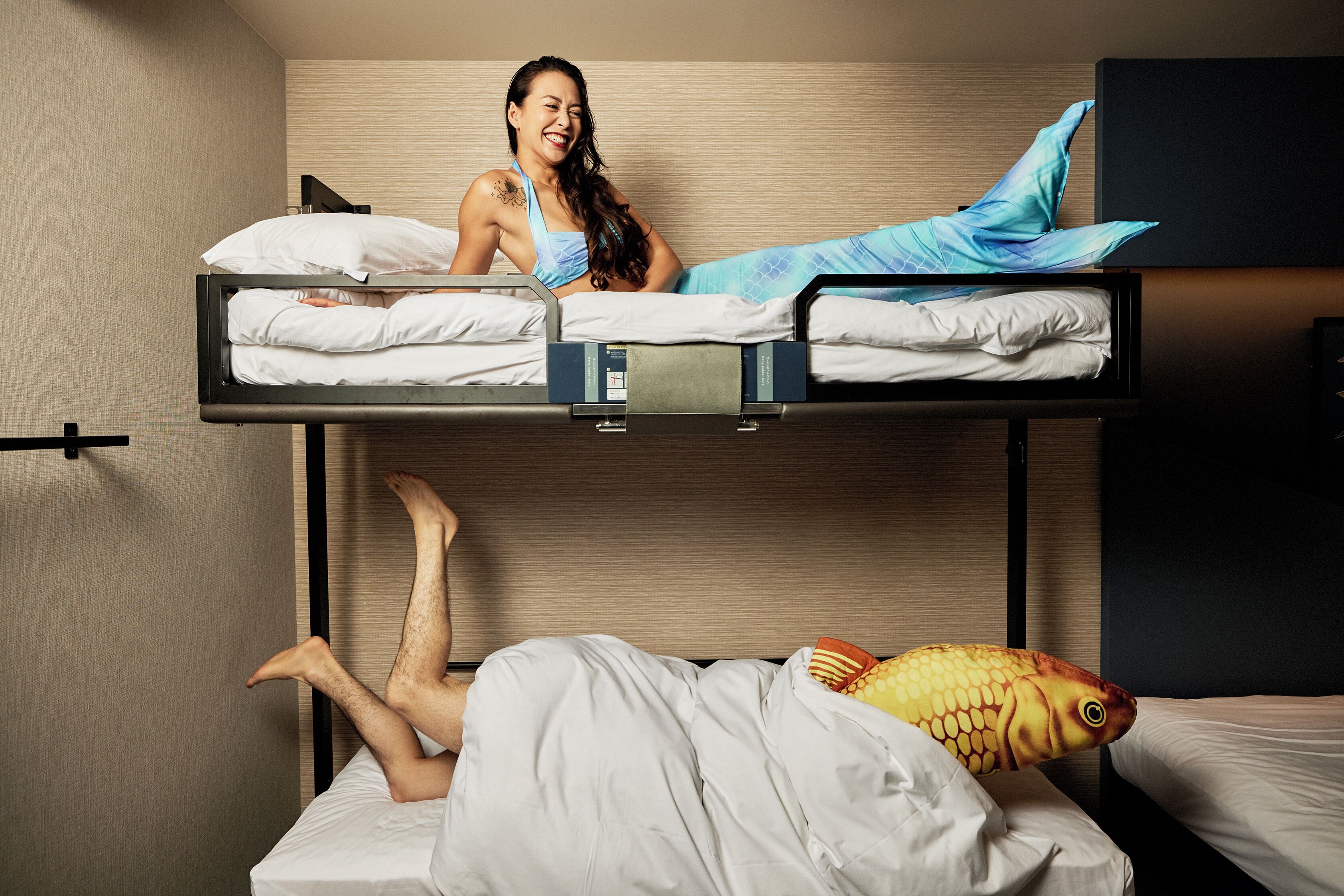 Uma cama de beliche com uma pessoa deitada na cama inferior e outra sentada na cama superior.