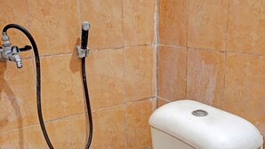 Um vaso sanitário com assento e tanque brancos, uma mangueira preta e uma parede com azulejos laranja.