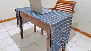 Uma mesa de madeira com um laptop, coberta por um tecido azul e branco listrado.