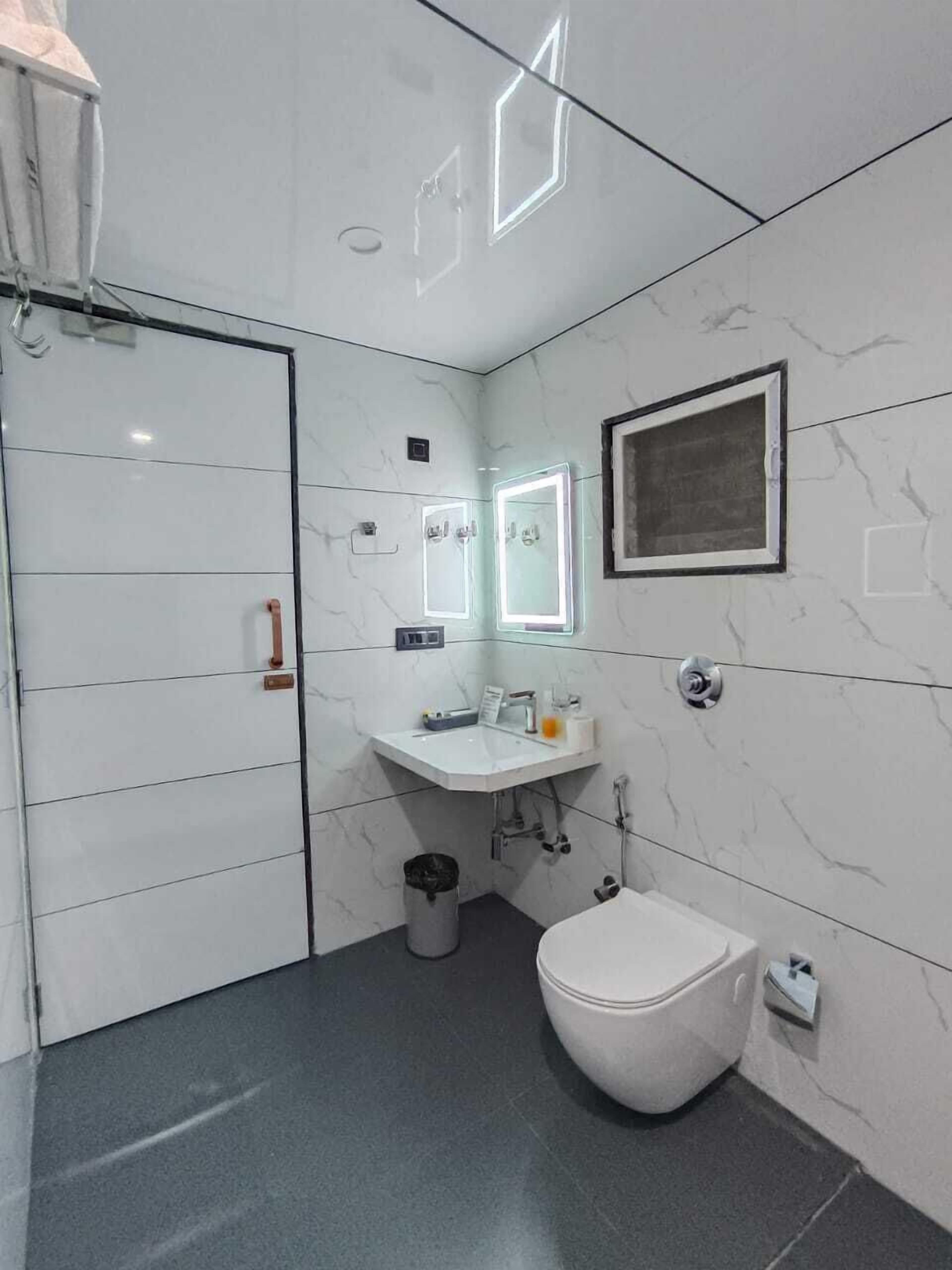 Um banheiro moderno com vaso sanitário branco, pia com espelho e área de chuveiro.