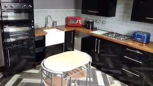 Uma cozinha com armários pretos, um micro-ondas vermelho, um fogão a gás e uma torradeira azul.