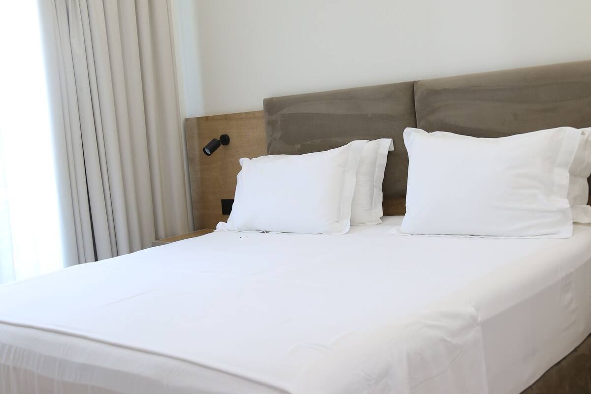 Cama bem arrumada com lençóis brancos em um quarto de hotel.