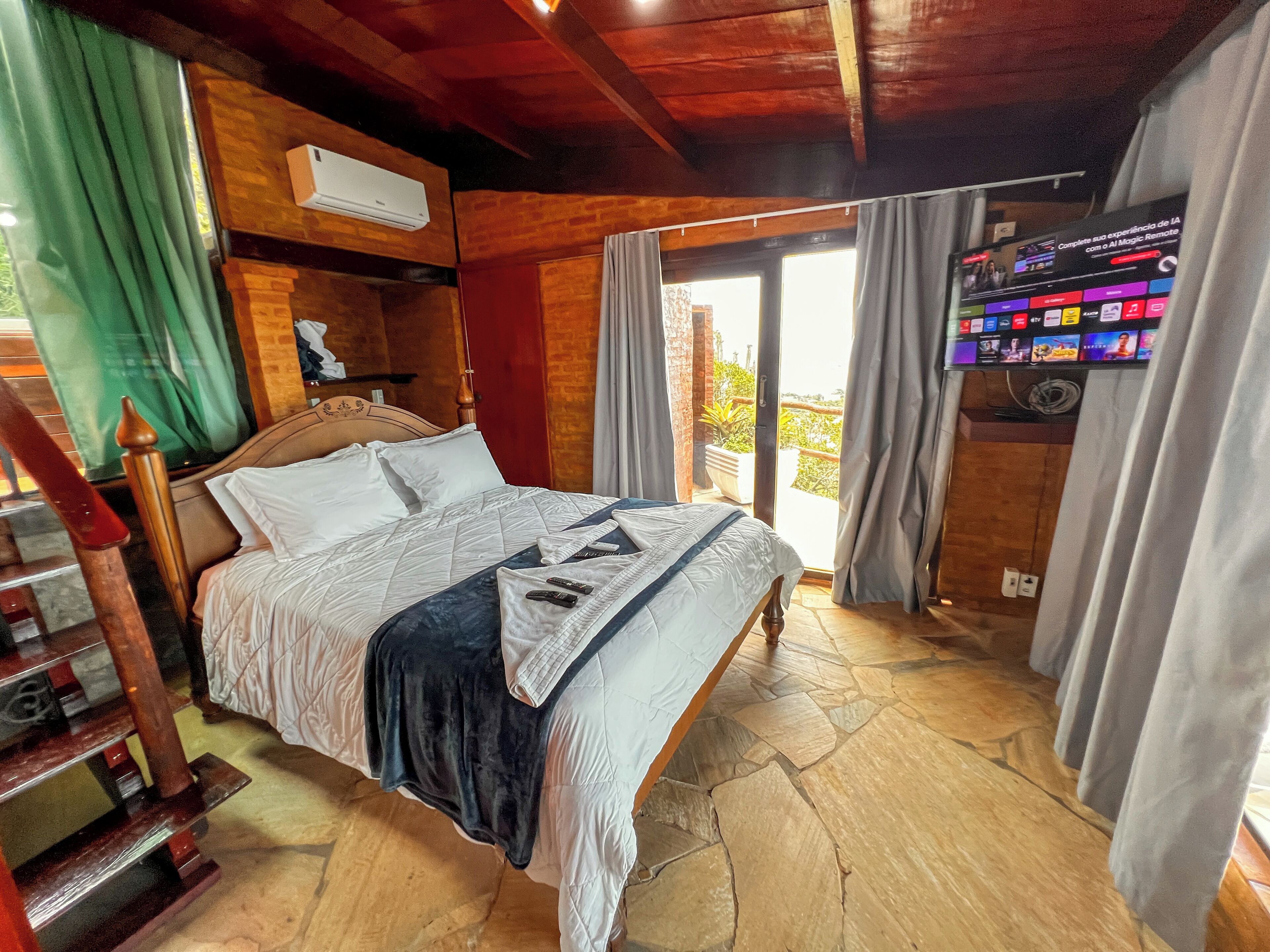 Quarto com cama, televisão presa na parede e escada.