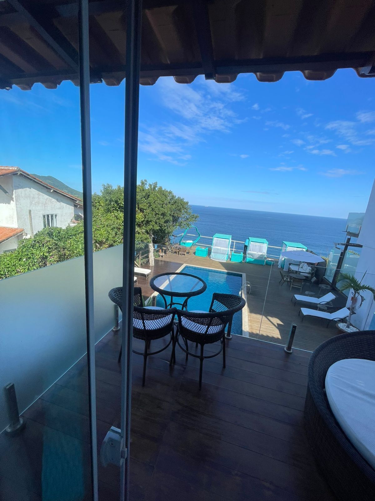 Uma varanda com piscina, espreguiçadeiras e vista para o oceano.