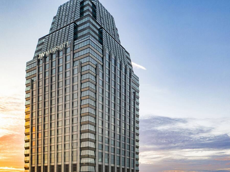 Um hotel JW Marriott imponente, com fachada moderna em vidro e seção superior marcante.