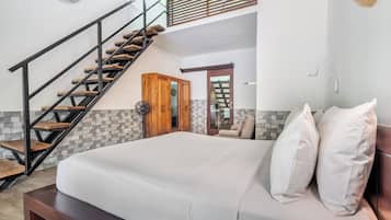 Quarto com cama, escada de madeira, porta e ventilador.