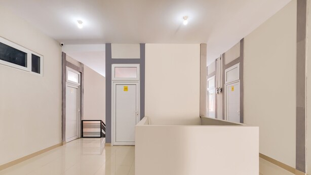 Um hall de hotel moderno com uma mesa de recepção, uma escada e uma porta com uma placa amarela.