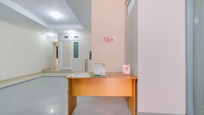 Um corredor com uma mesa de madeira, um calendário e uma placa na parede.