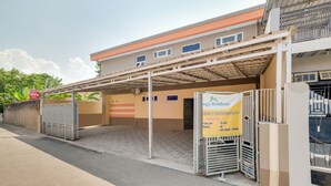 Um edifício com entrada coberta, uma placa e área murada.