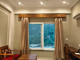 Quarto com janela, cabeceira de madeira e uma mesa.