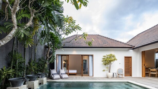 Uma villa moderna com piscina, deck de madeira e vegetação tropical exuberante.