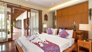 Quarto de hotel com uma cama grande, guarda-roupa de madeira e vista para um corredor com portas que dão para outros quartos.