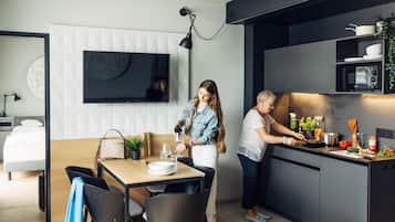 Cozinha moderna com área de jantar, televisão de tela plana na parede e pequena mesa de jantar com cadeiras.