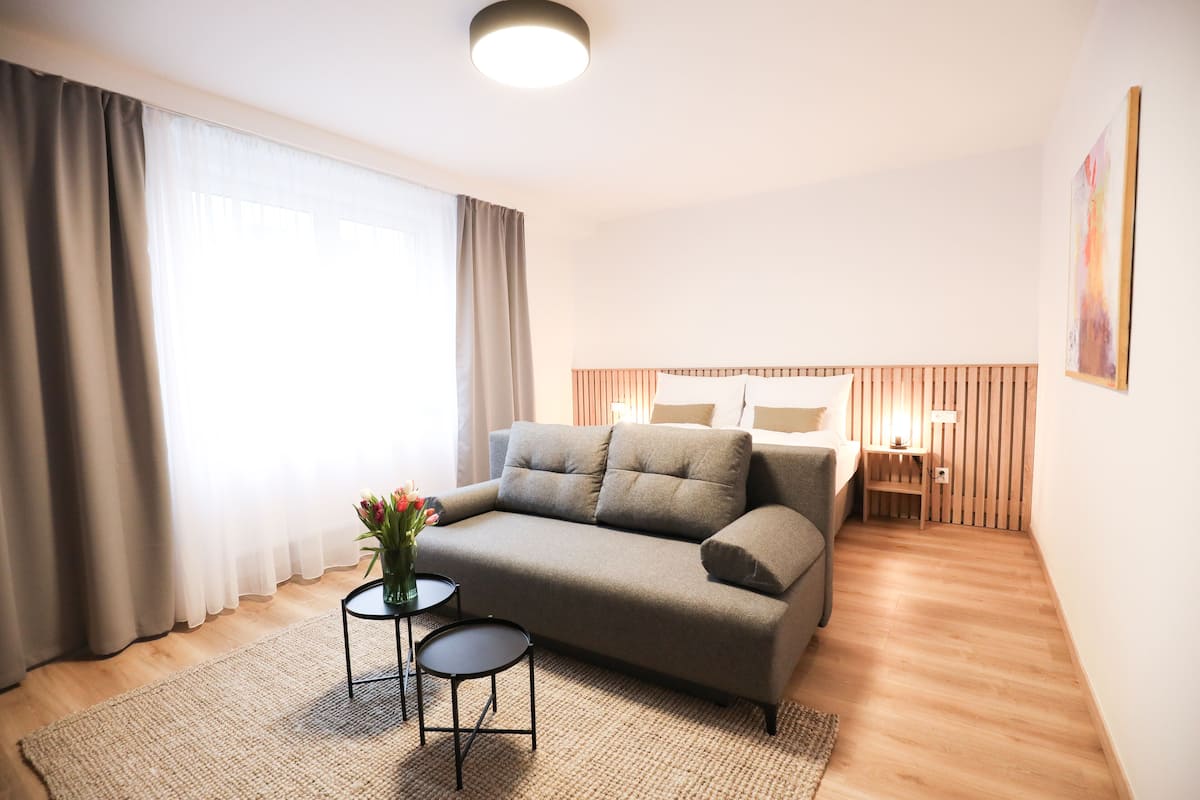 Quarto de hotel moderno com sofá, uma mesinha e mesa de cabeceira.