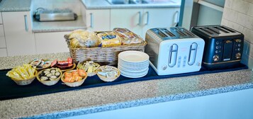 Uma bancada de cozinha com diversos alimentos, uma torradeira e uma cesta de pão.