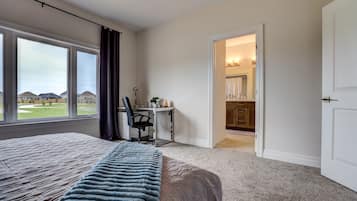 Quarto com cama grande, escrivaninha e vista para um jardim.